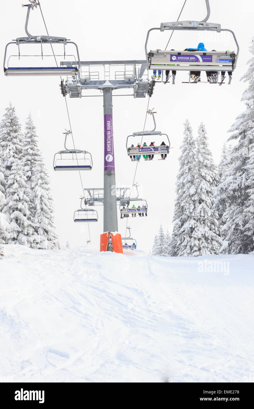 Ski lift in mountain with paths of skies and snowboards. Skiers in a ...