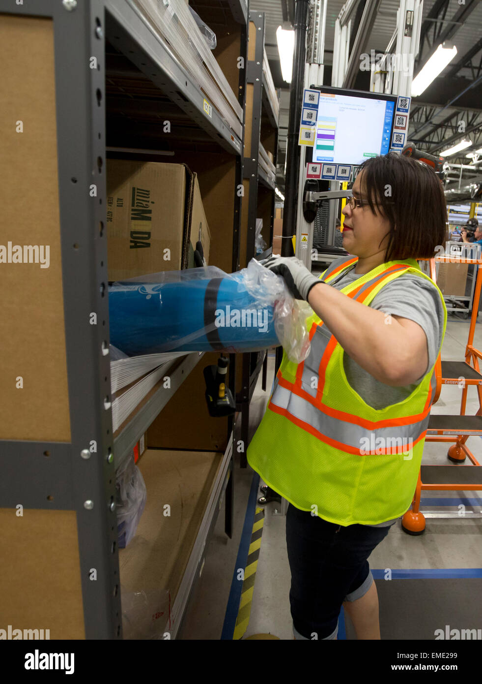 Female Hispanic employee at Amazon fulfillment center tracks packages ...