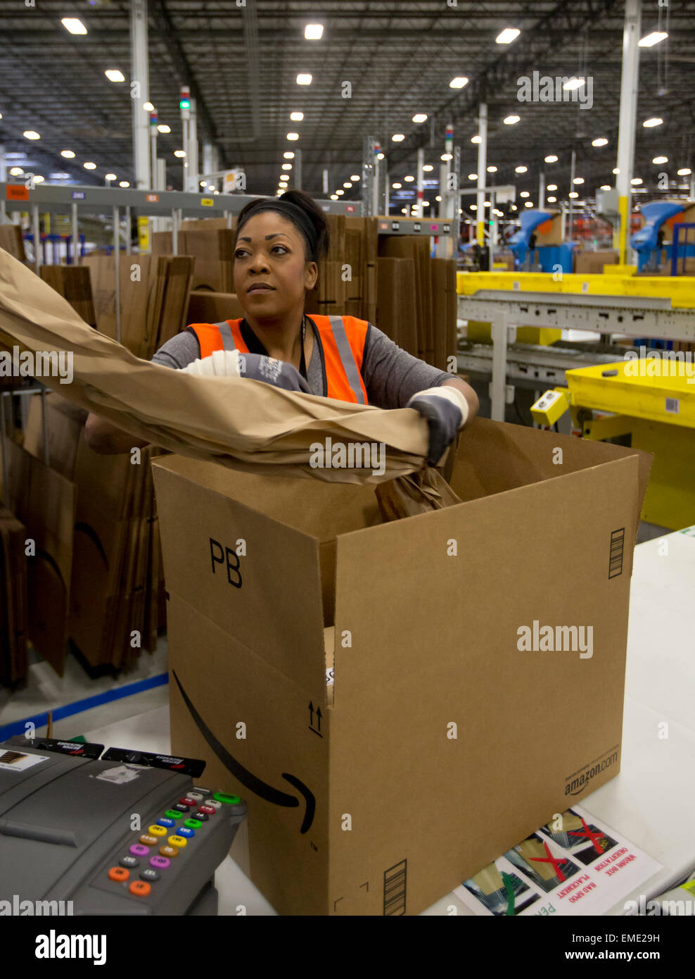 African-American female employee packages items in boxes at Amazon ...