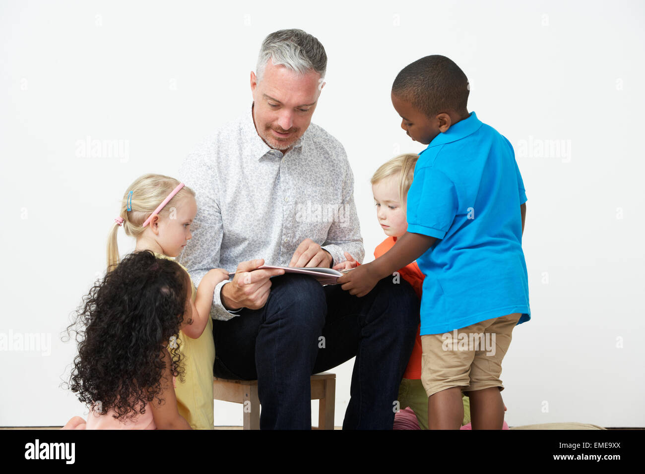 Pre School Teacher Reading Story To Children Stock Photo - Alamy
