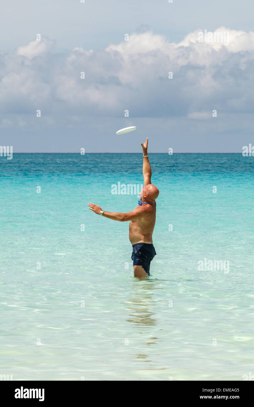 Bald man catches a plate for frisbee on horizon on deep blue see and ...