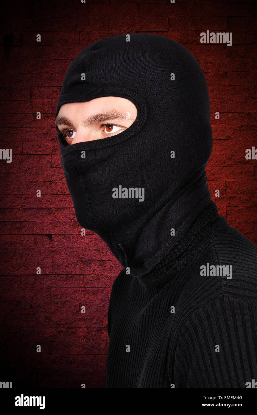 robber in mask on a green wall background Stock Photo - Alamy