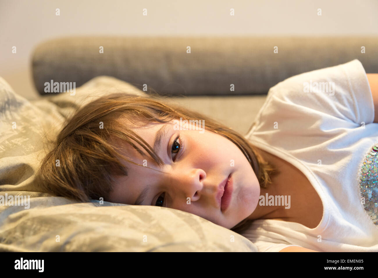 Little girl watching TV on the couch stretched Stock Photo - Alamy
