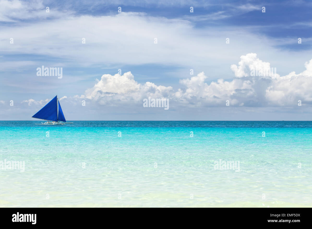 Blue sailing boat on horizon of deep blue sea. Big white clouds in the ...