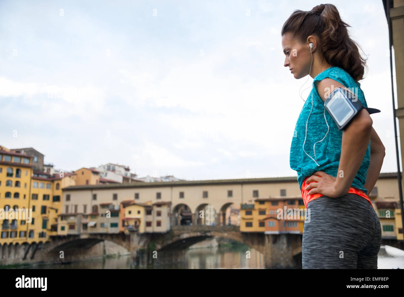 Thoughtful fitness woman standing in front of ponte vecchio in florence ...