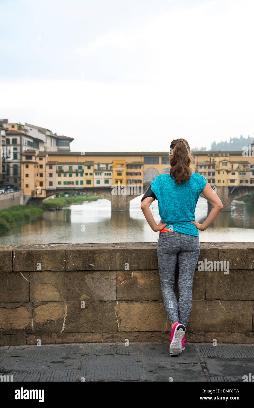 Fitness woman looking on ponte vecchio in florence, italy. rear view ...