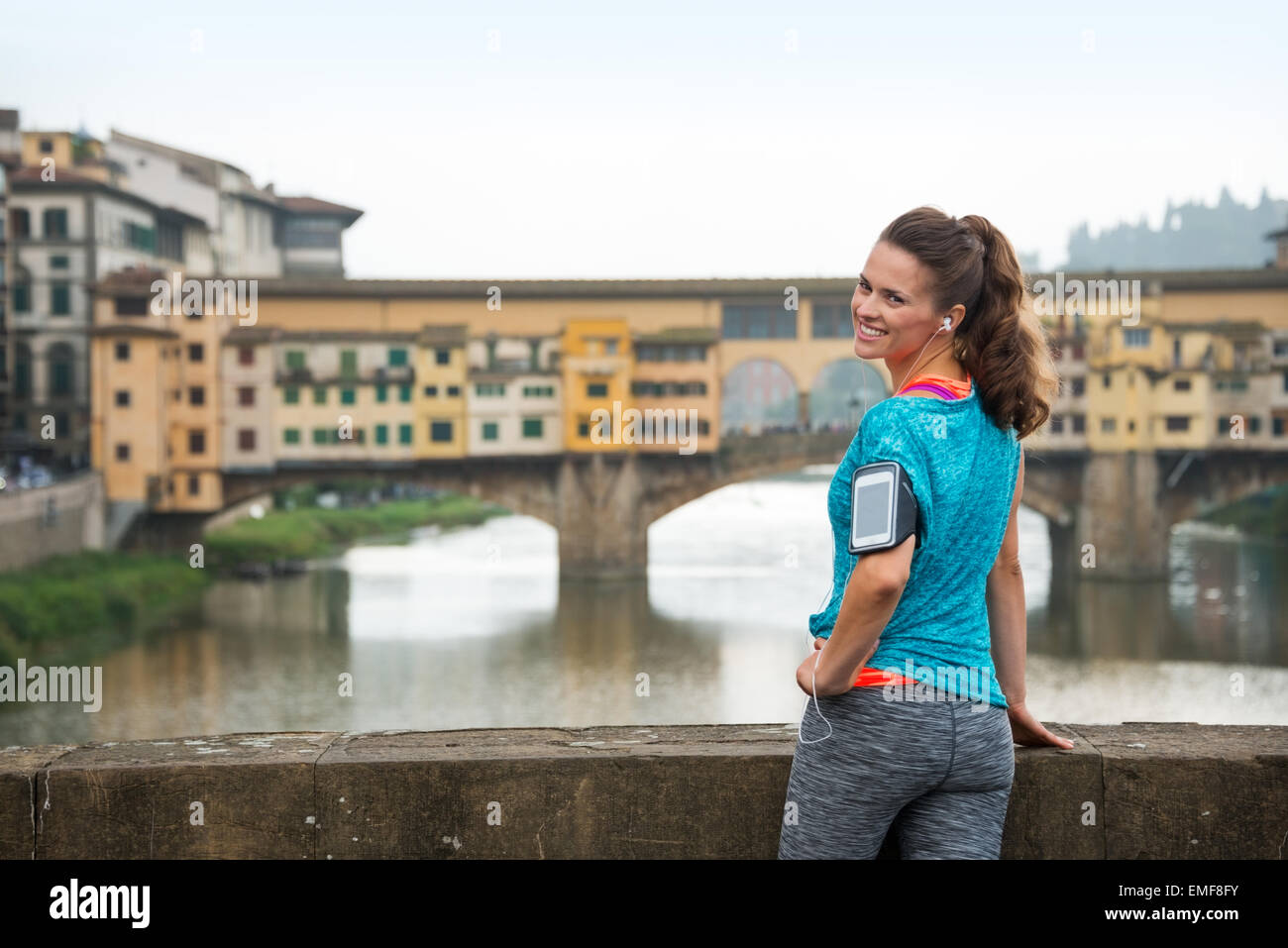 Smiling fitness woman standing in front of ponte vecchio in florence ...