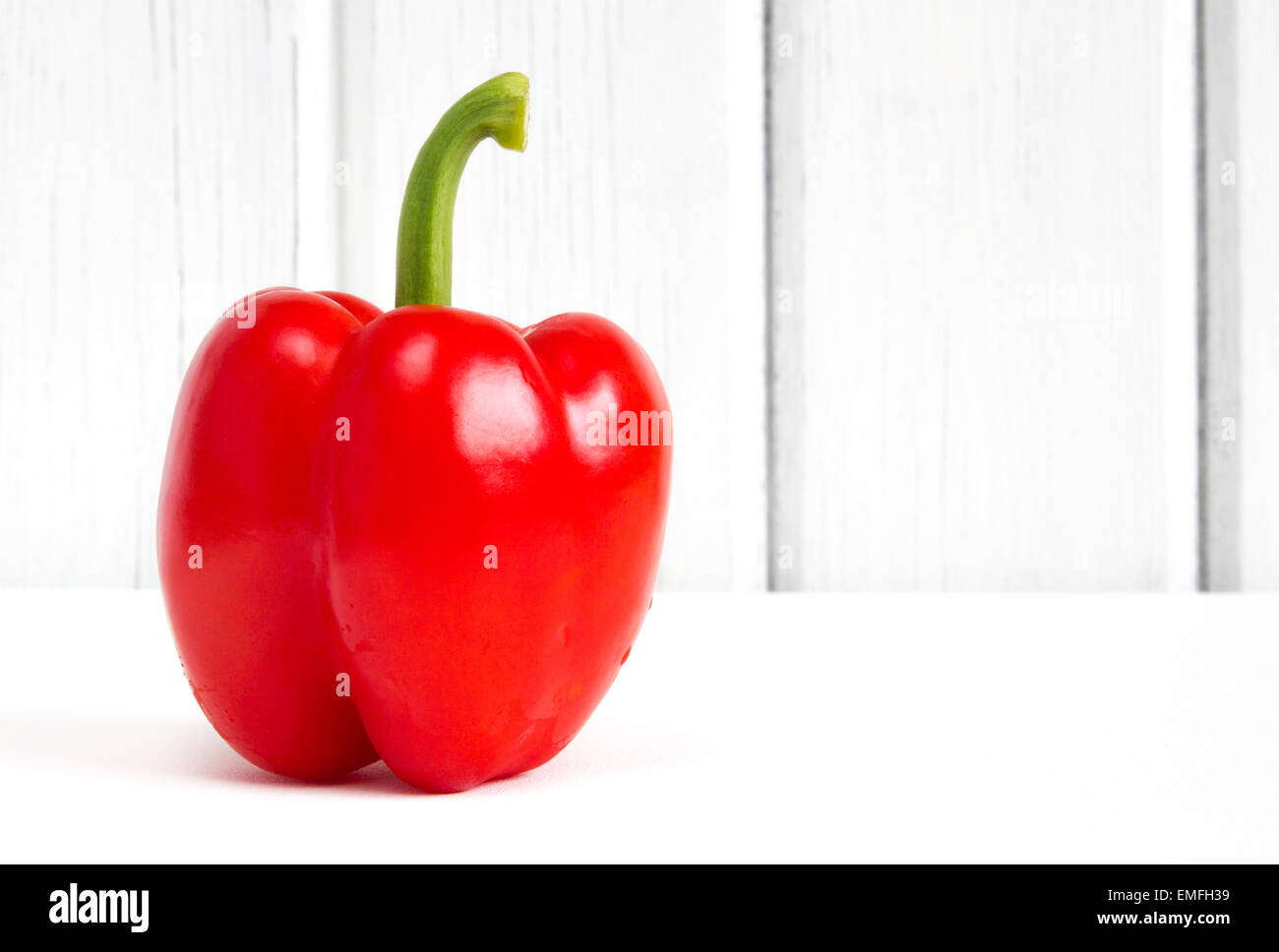 Fresh red pepper (Capsicum) against white wood background with ...