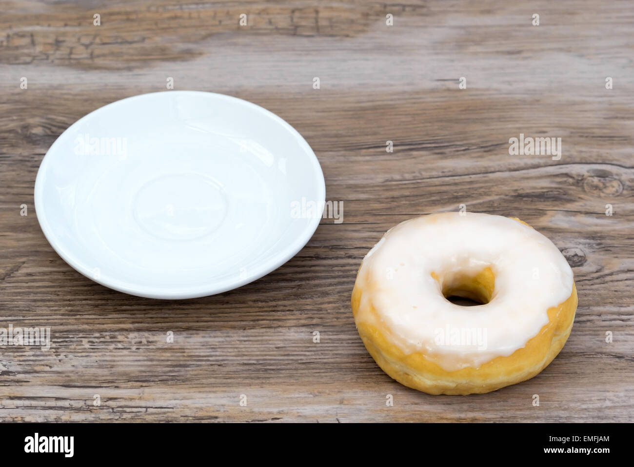 Glazed donut next to an empty plate from above - foodshot with slightly ...