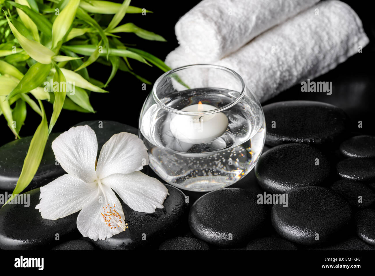 spa concept of white hibiscus flower, bamboo, round vase and towels on ...