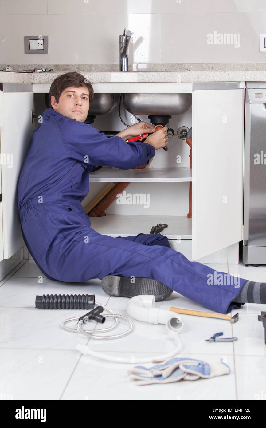 Plumber fixing kitchen Stock Photo - Alamy