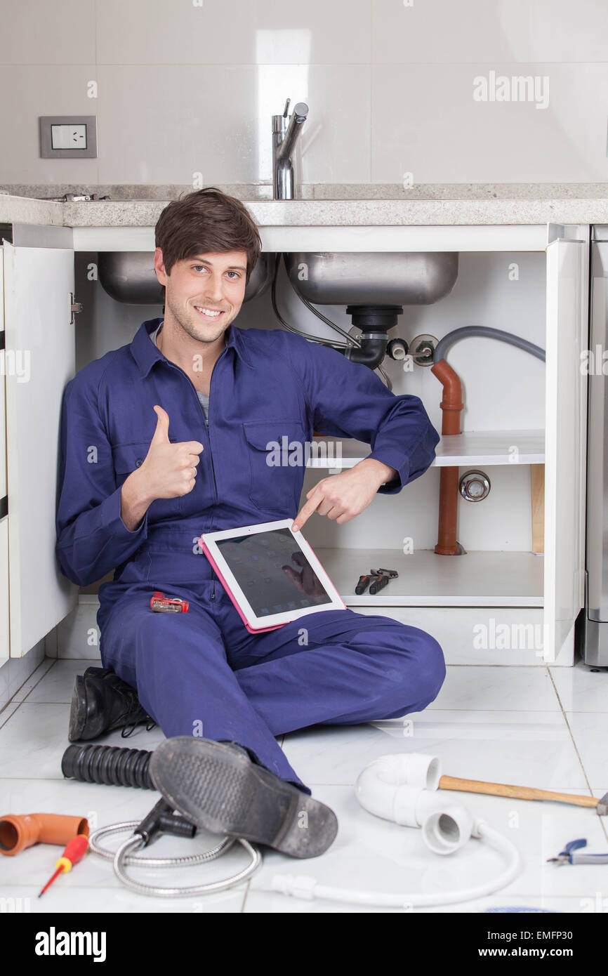 Plumber fixing kitchen Stock Photo - Alamy