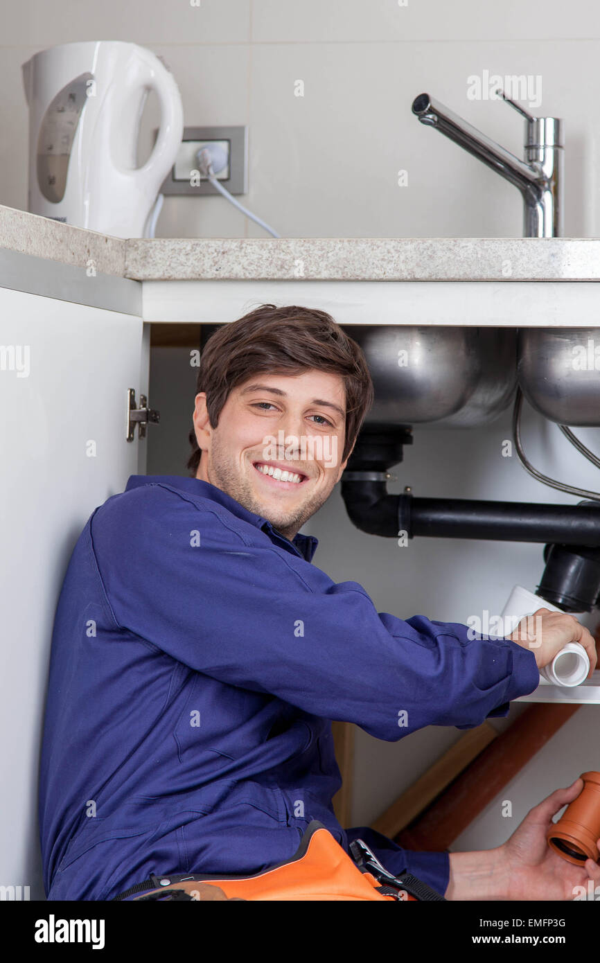 Plumber fixing kitchen Stock Photo - Alamy