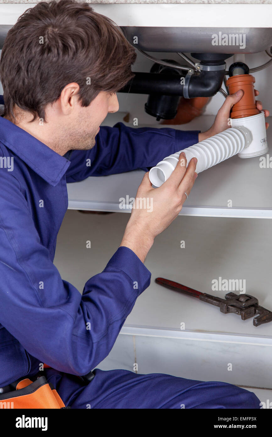 Plumber fixing kitchen Stock Photo - Alamy