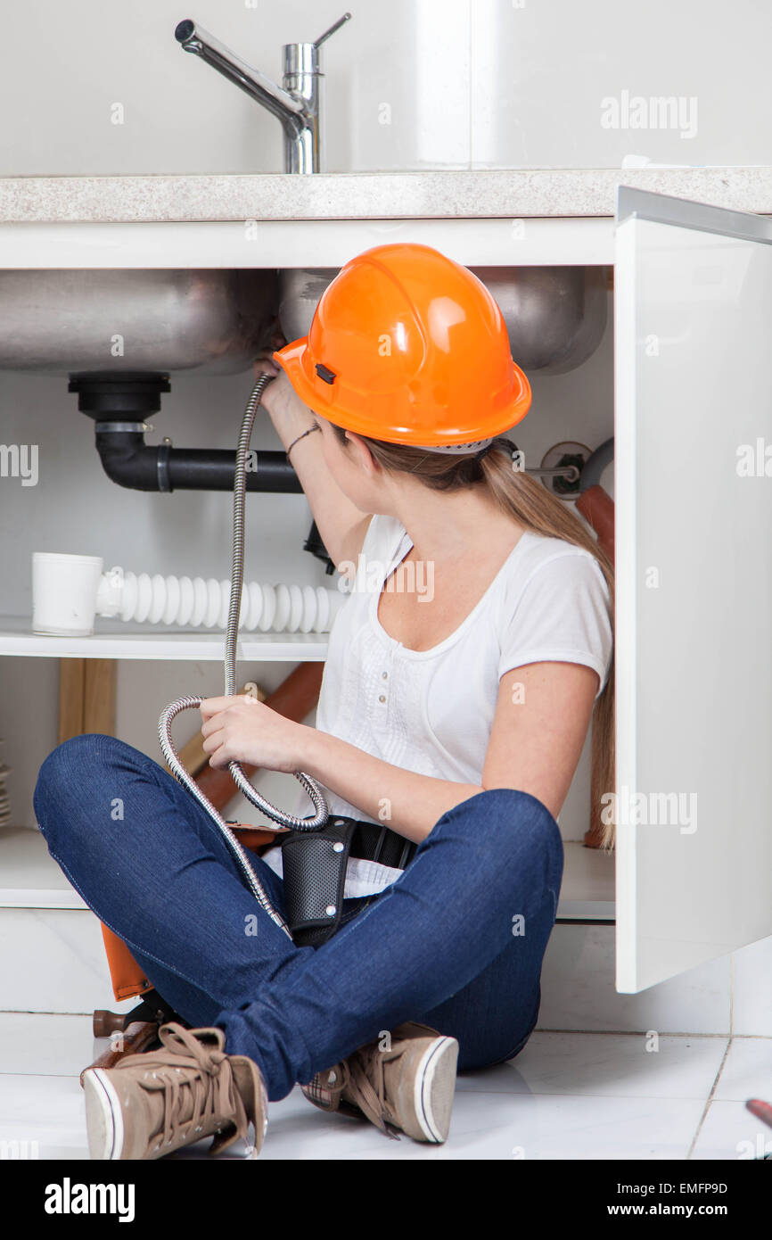 Woman plumber in the kitchen Stock Photo - Alamy