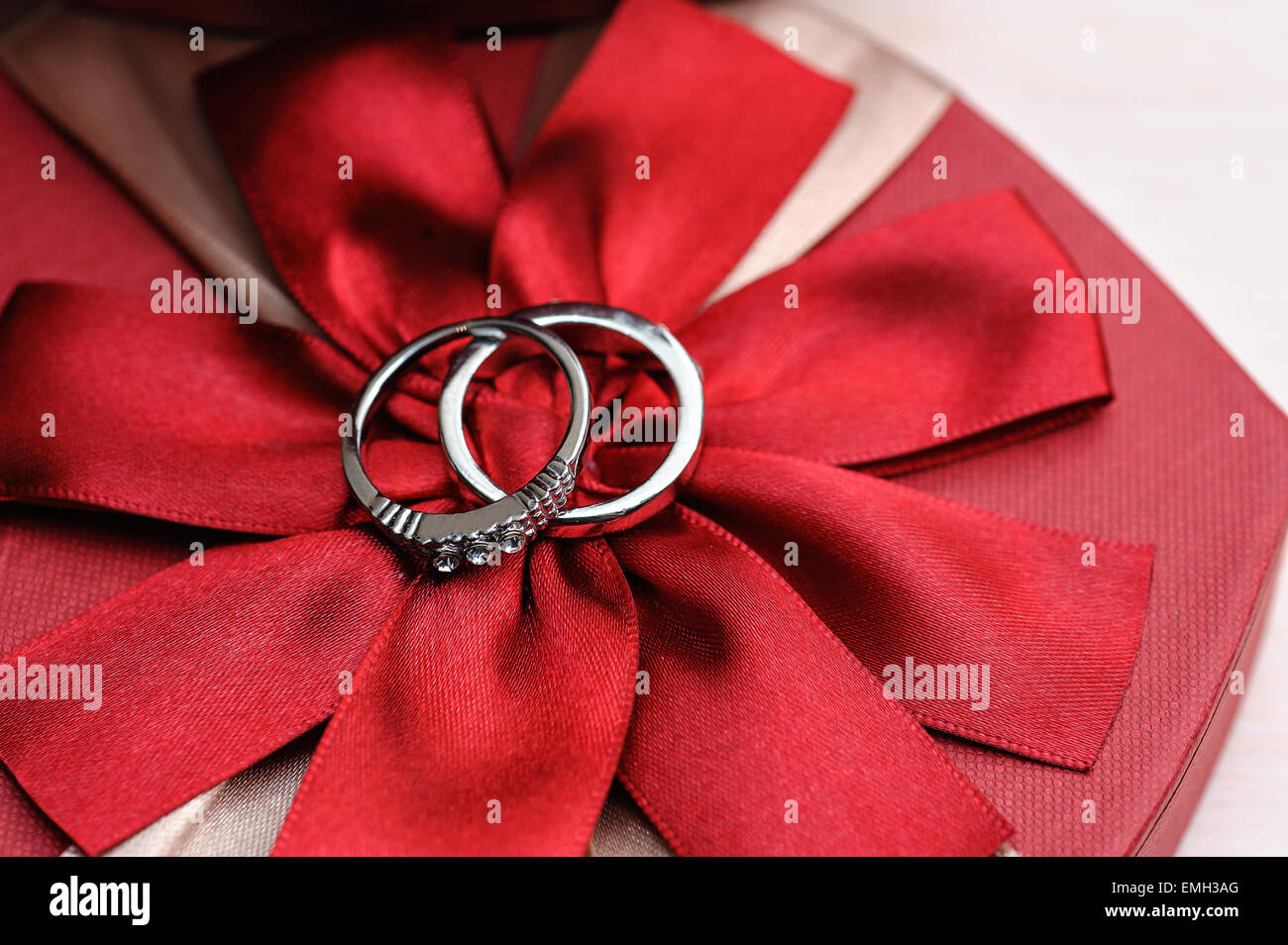 two wedding rings on a red ribbon background Stock Photo - Alamy
