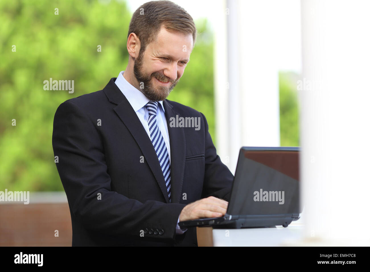 Happy business man working browsing internet in a laptop outdoor with a ...