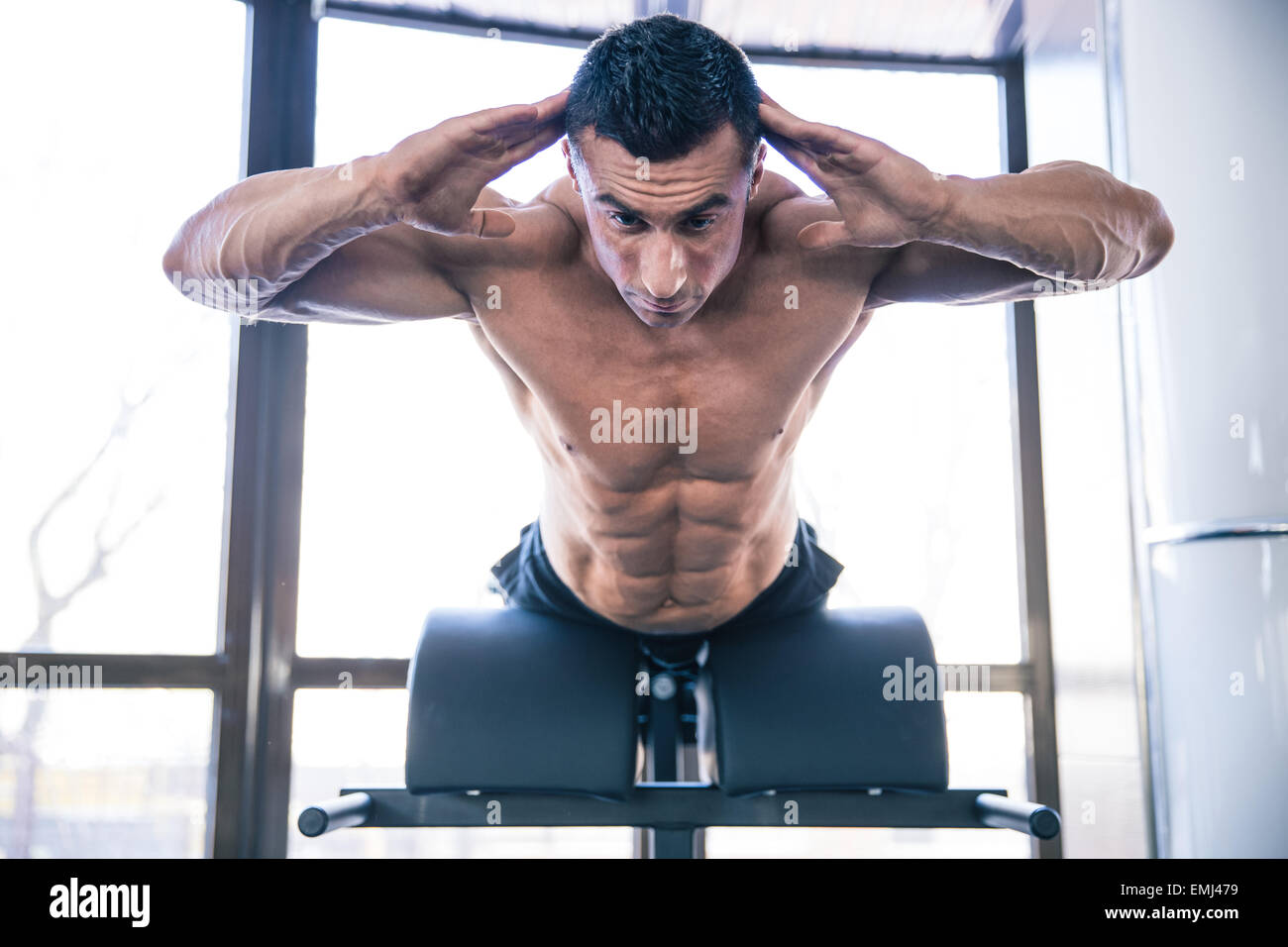Handsome muscular man flexing back muscles on bench in gym Stock Photo ...