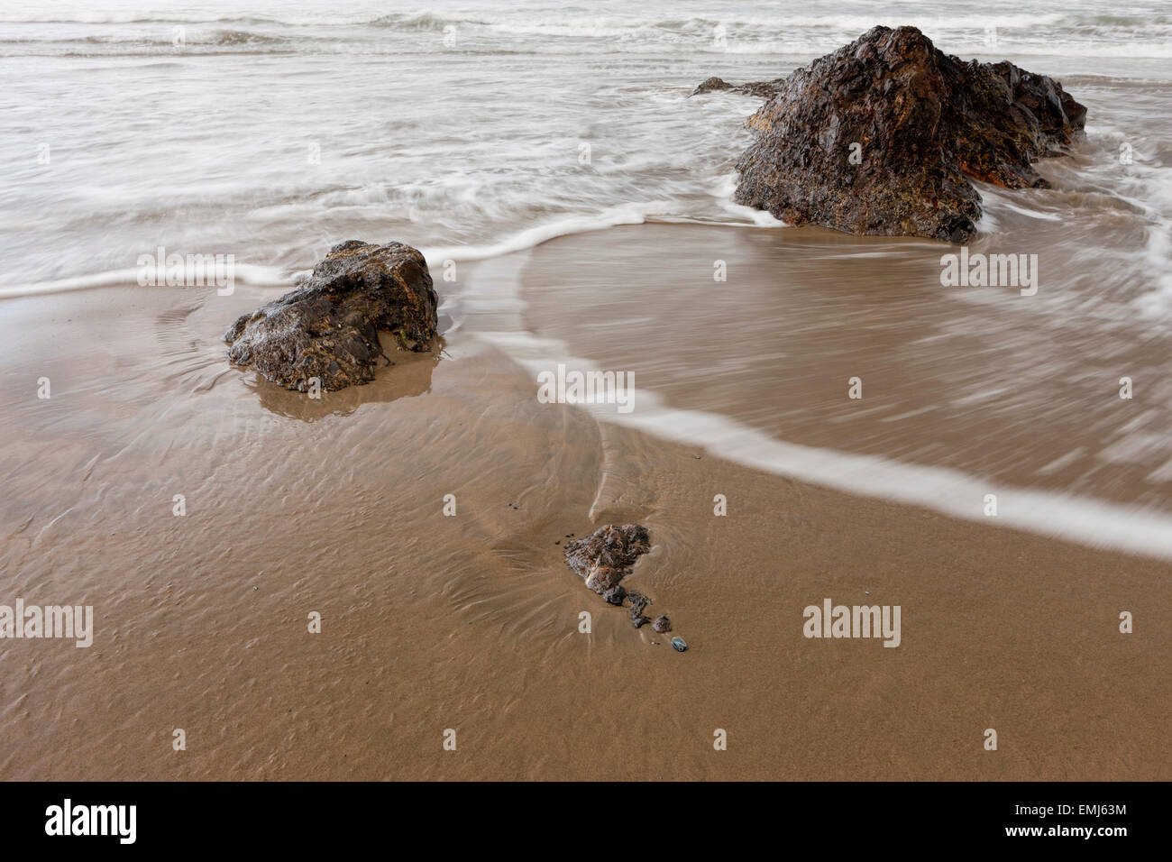 Water rushes around rocks on beach Stock Photo - Alamy