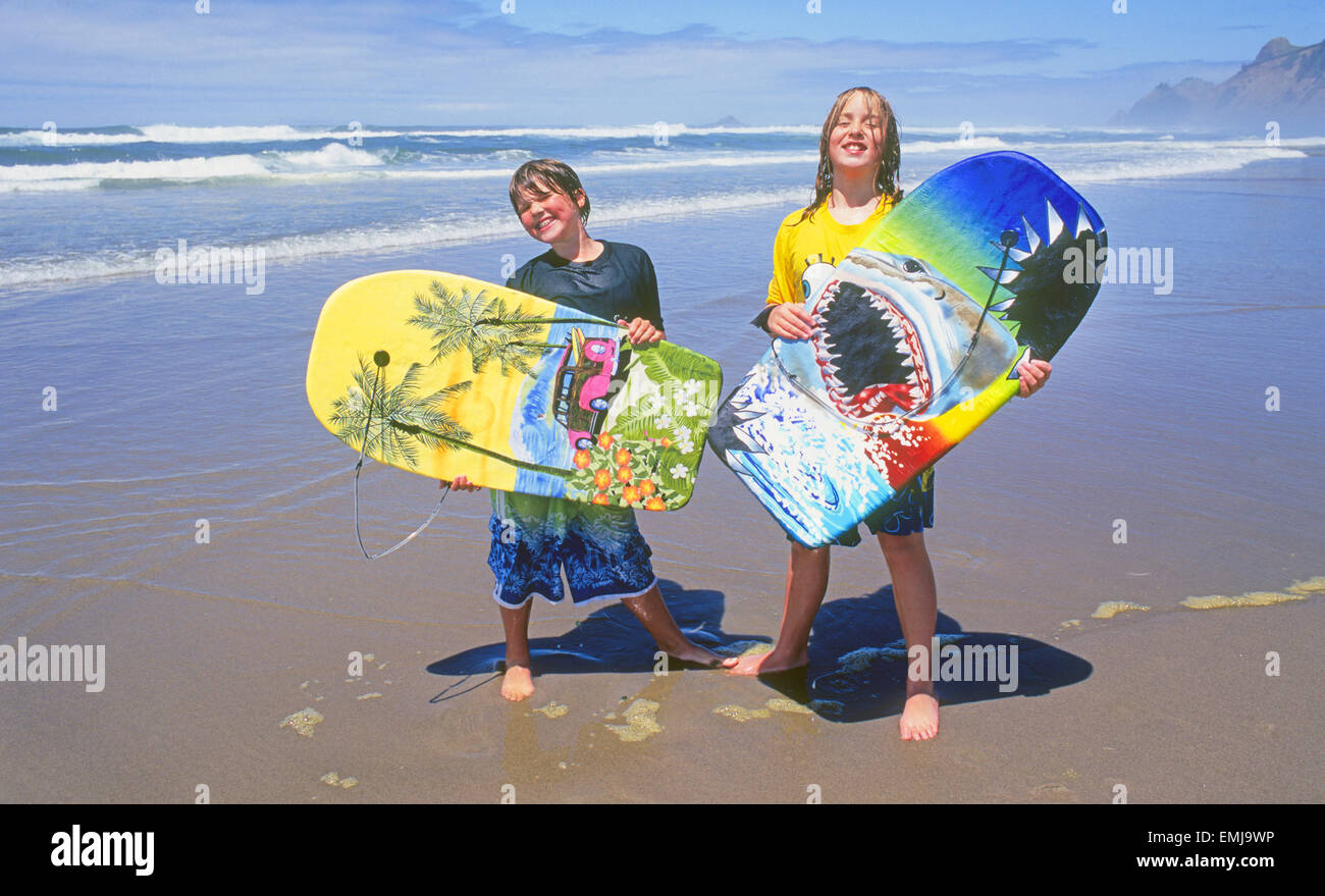 Two pre-teen girls with boogie boards on a beach on the Oregon Pacific ...