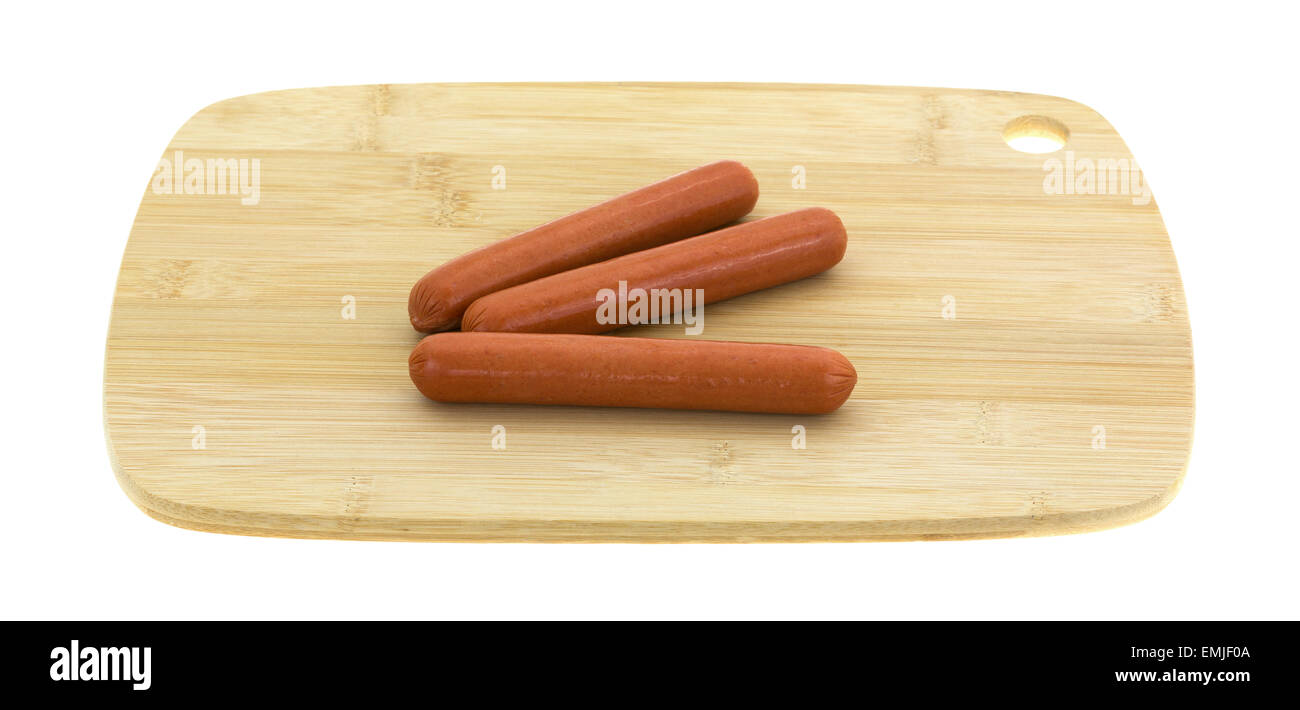 Three all beef hot dogs on a wood cutting board isolated on a white ...