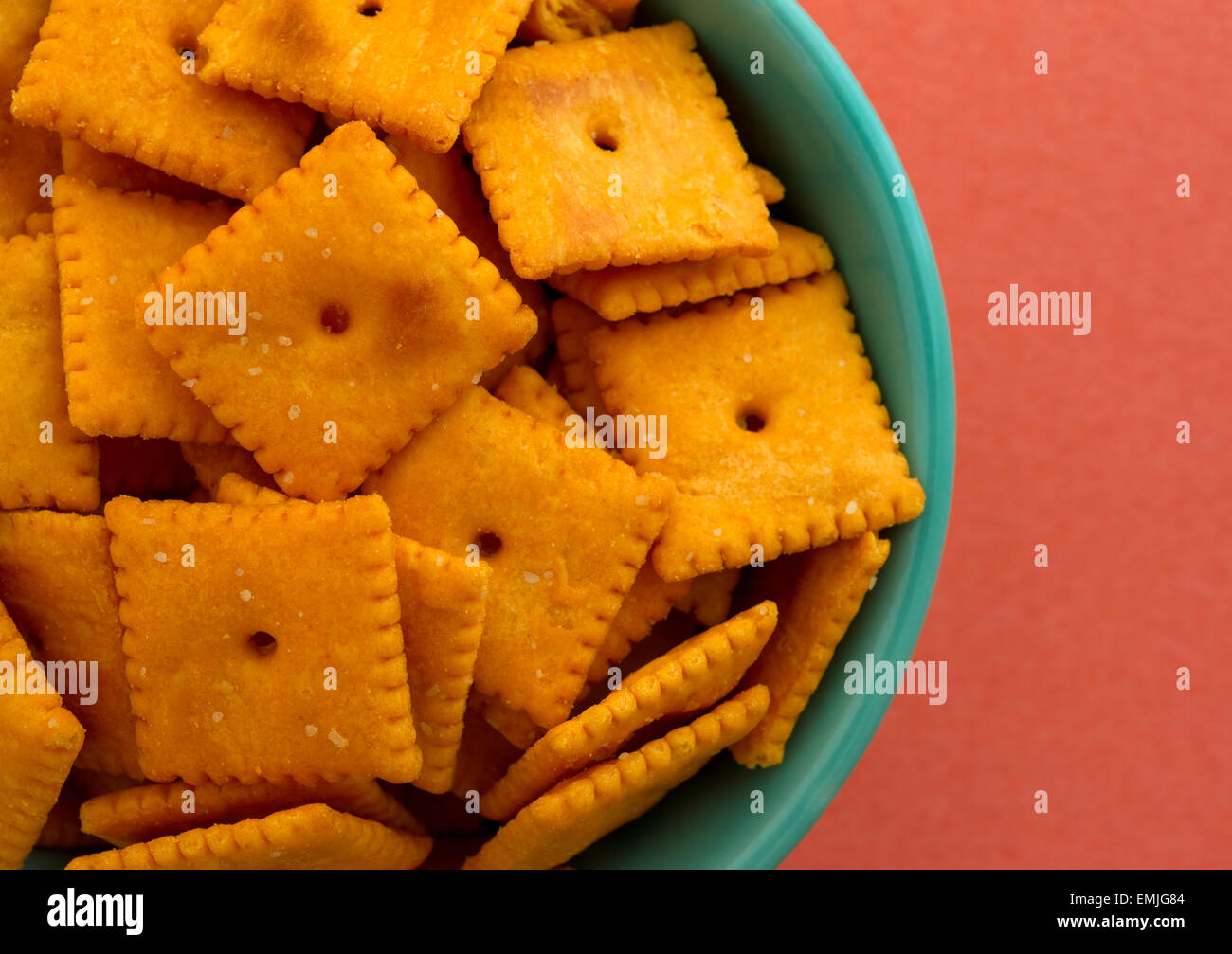 Top close view of a bowl of cheese crackers atop an orange background ...