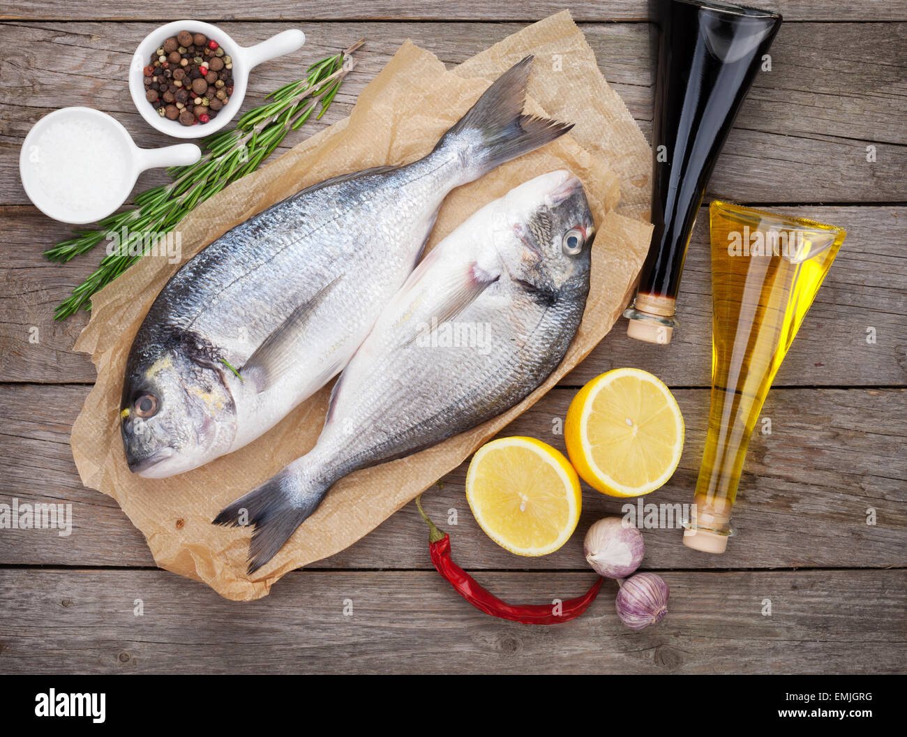 Fresh dorado fish cooking with spices and condiments on wooden table ...