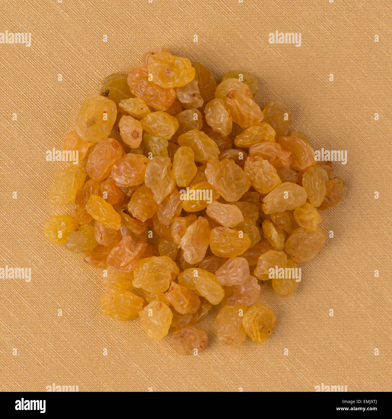 Top view of circle of golden raisins against yellow vinyl background ...