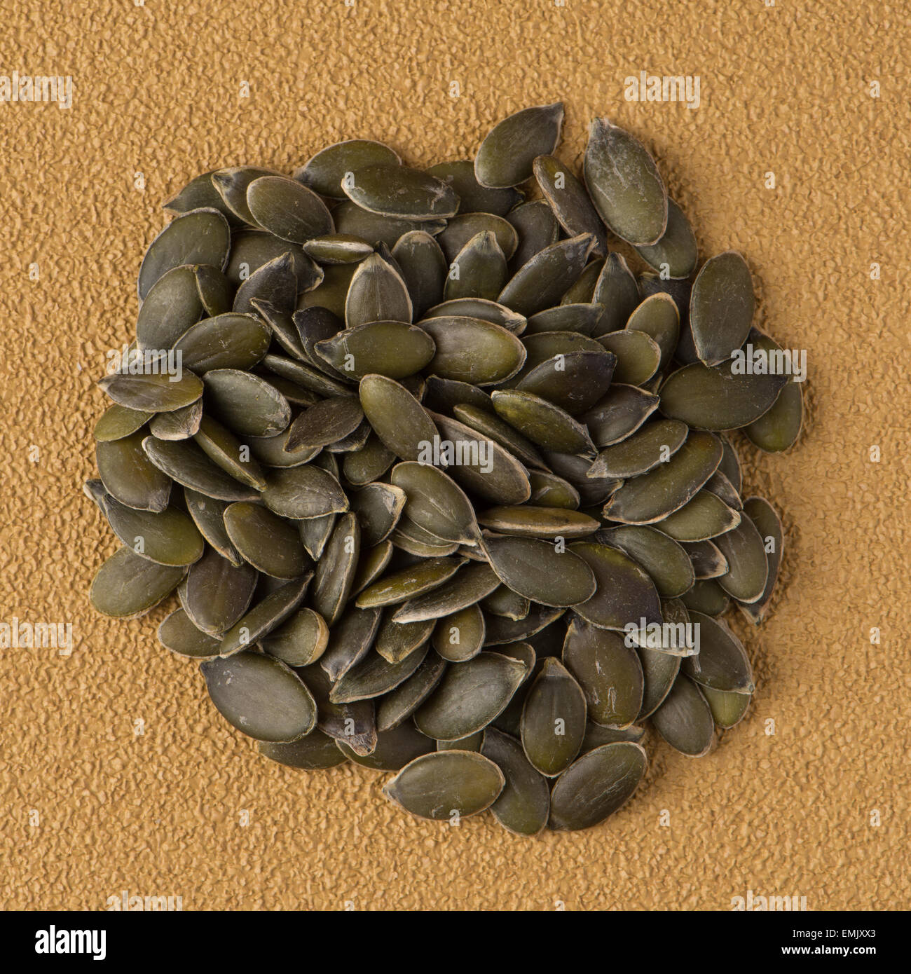 Top view of circle of pumpkin seeds against yellow vinyl background ...