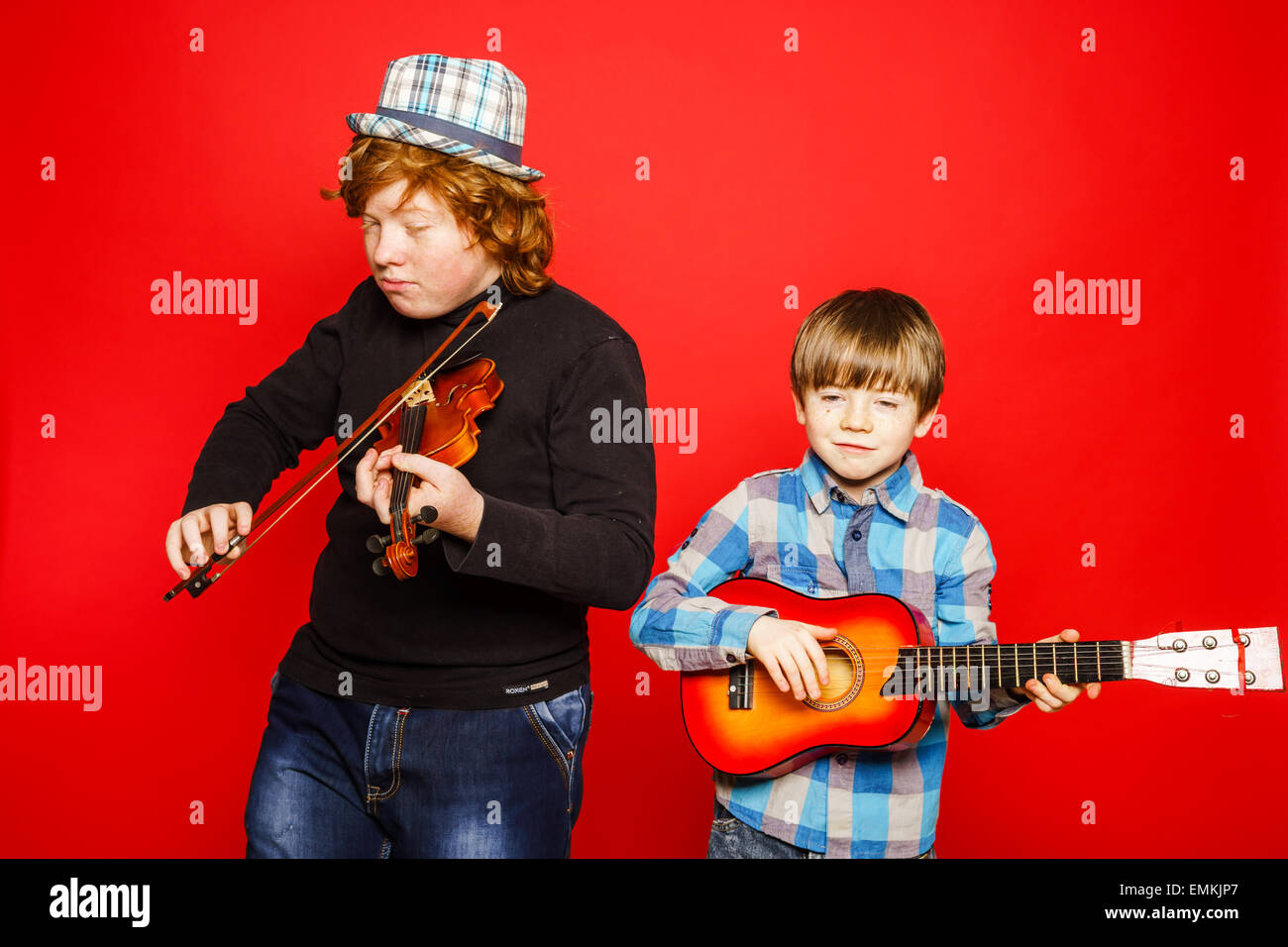 Two funny red-hair brothers playing music, isolated on red Stock Photo ...
