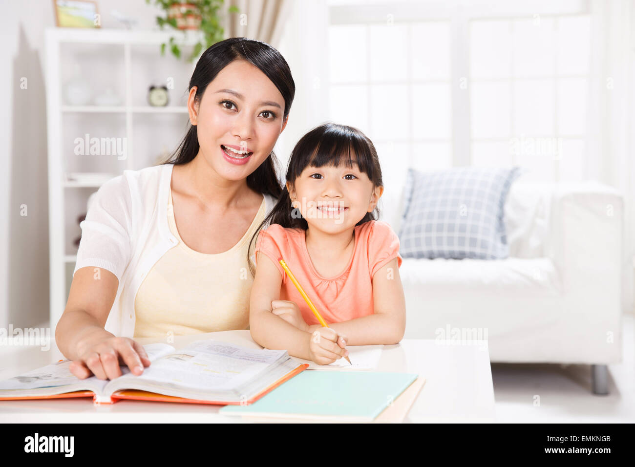 Mother guiding daughter study in the living room Stock Photo - Alamy