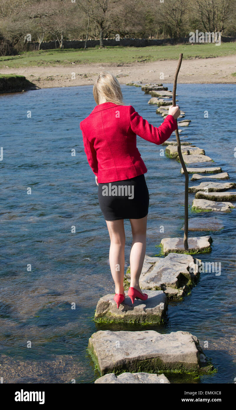 Stepping stones smartly dressed woman crossing river using a tree ...