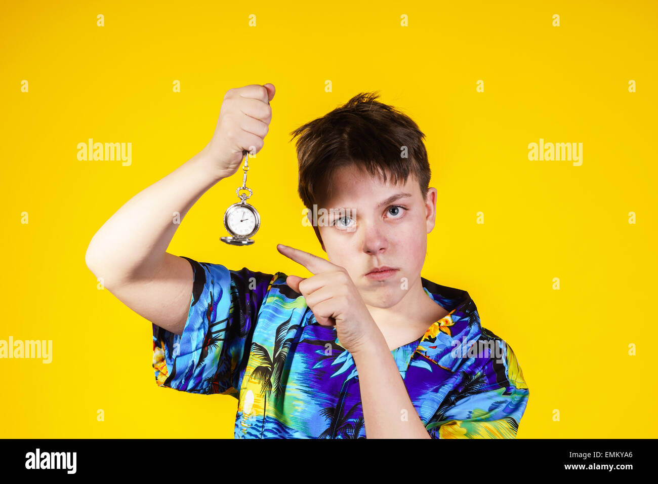 Affective teenage boy with watch showing time, isolated on yellow ...