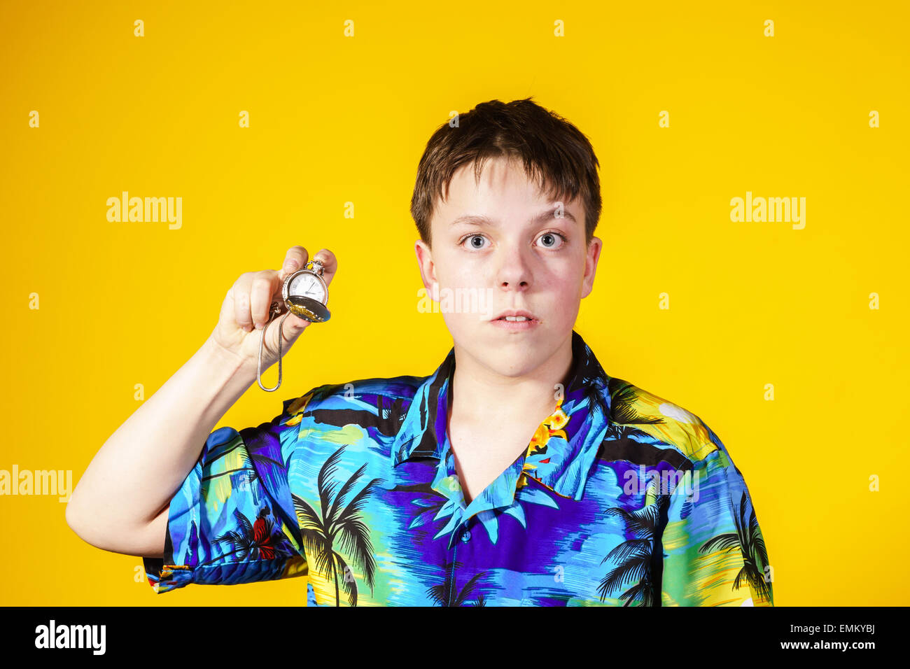 Affective teenage boy with watch showing time, isolated on yellow ...