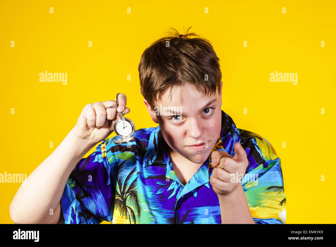 Affective teenage boy with watch showing time, isolated on yellow ...