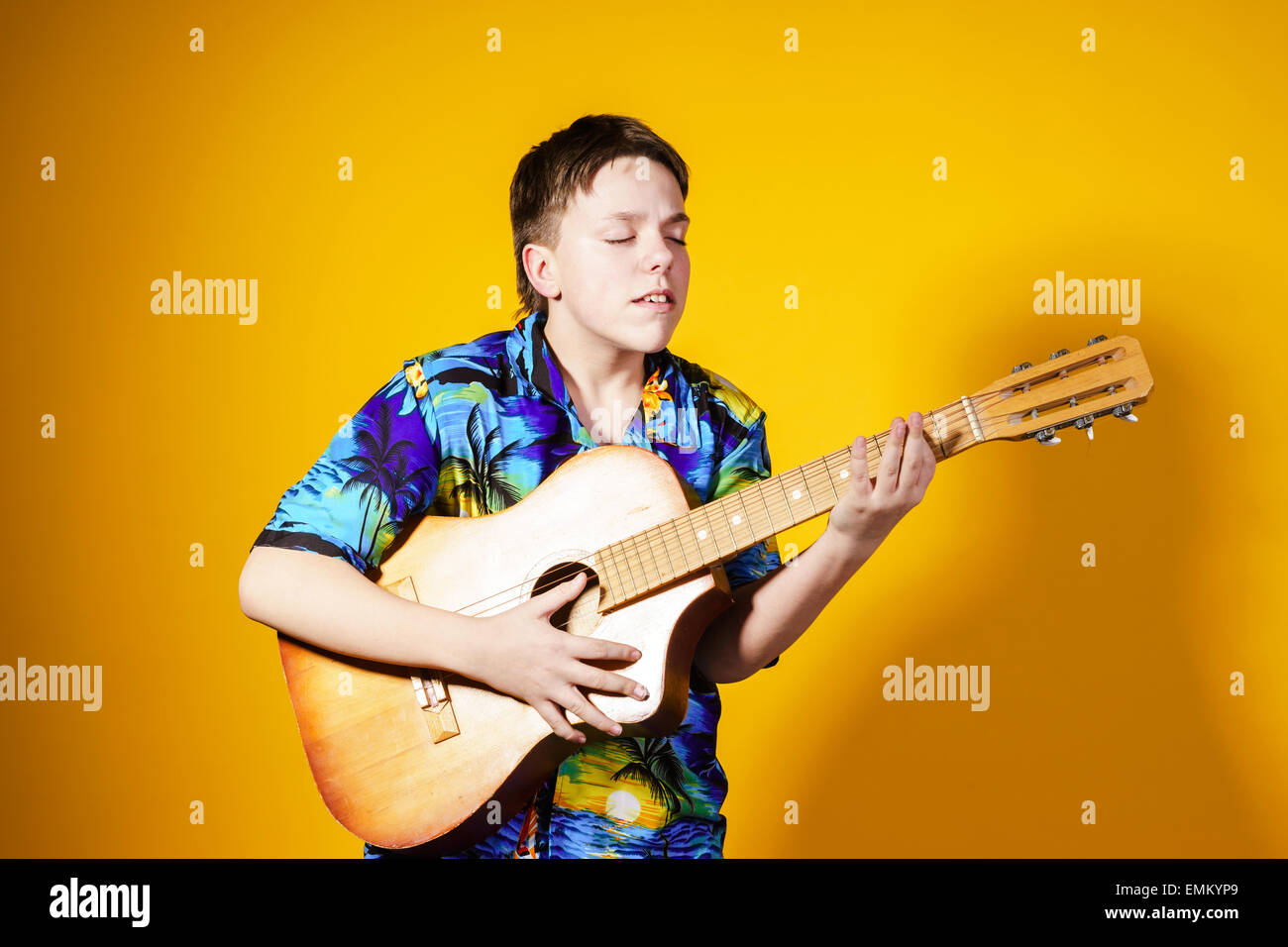 Affective teenage boy with guitar. Music concept. Isolated on yellow ...