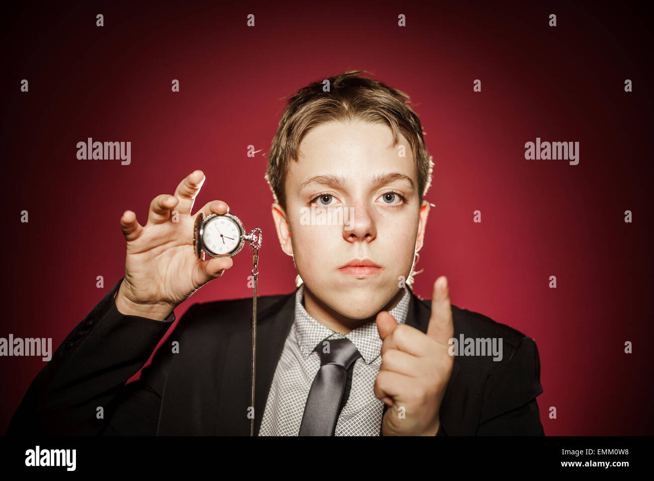 Affective teenage boy with watch showing time, isolated on red, concept ...