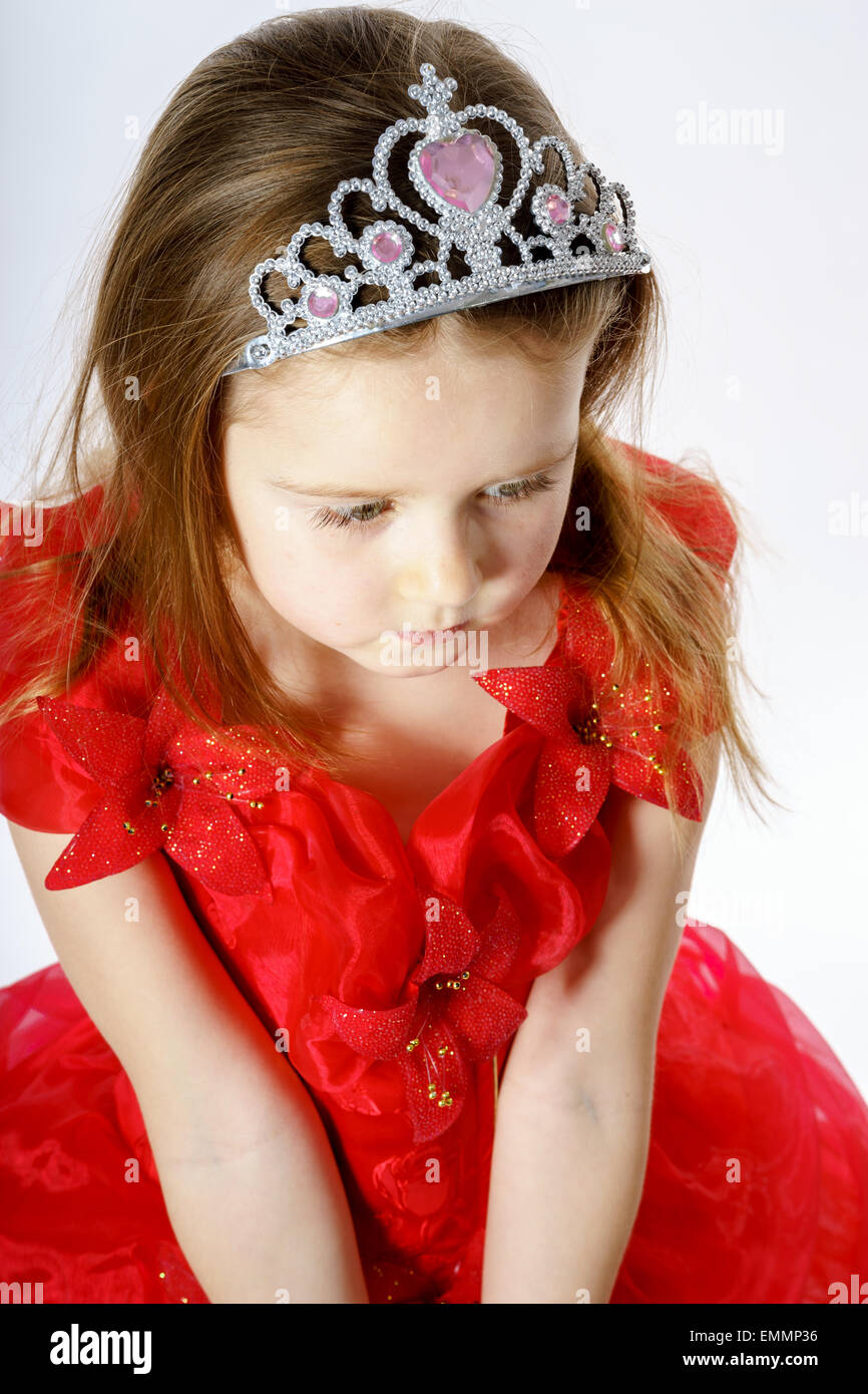 Cute little princess dressed in red with crown on her head posing in ...