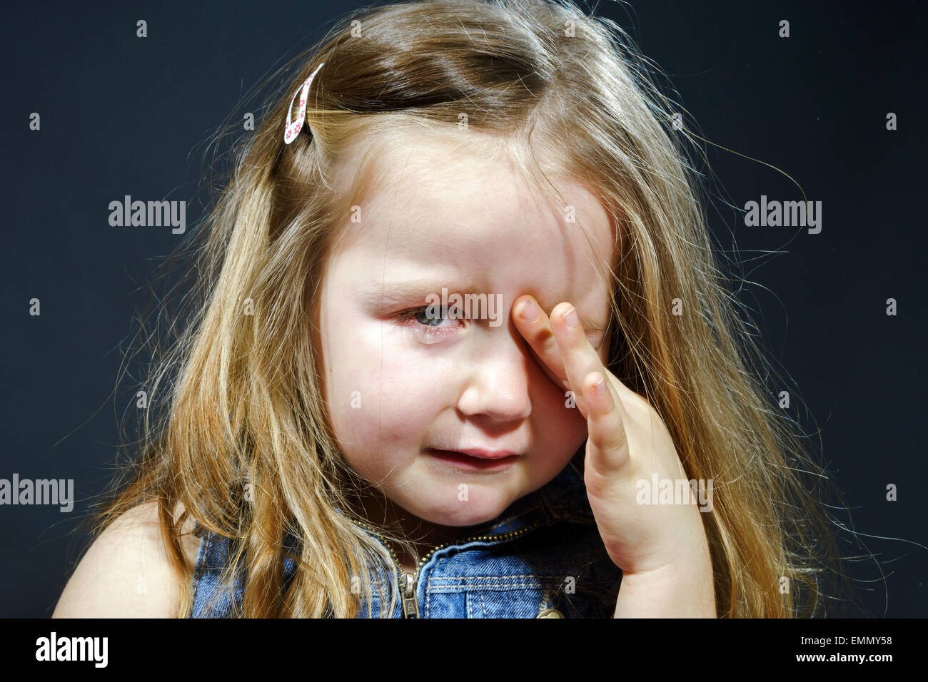 Crying cute little girl with focus on her tears on dark background ...
