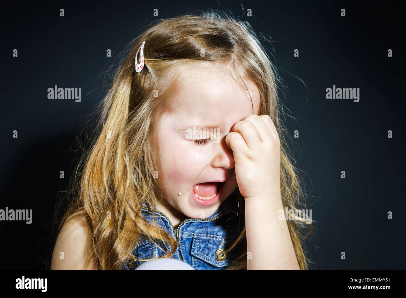 Crying cute little girl with focus on her tears on dark background ...