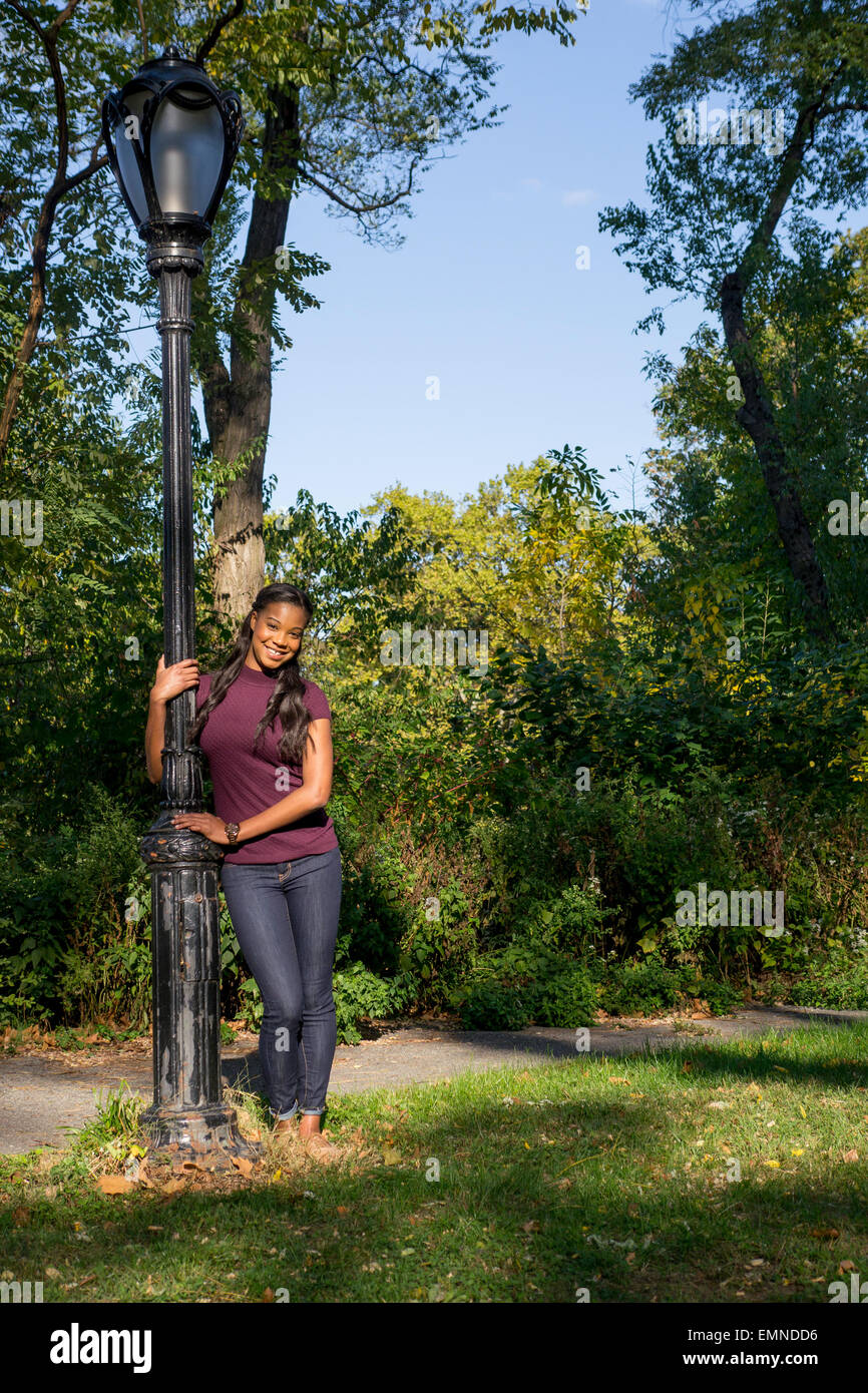 a smiling woman holding a lamp post in a park Stock Photo - Alamy