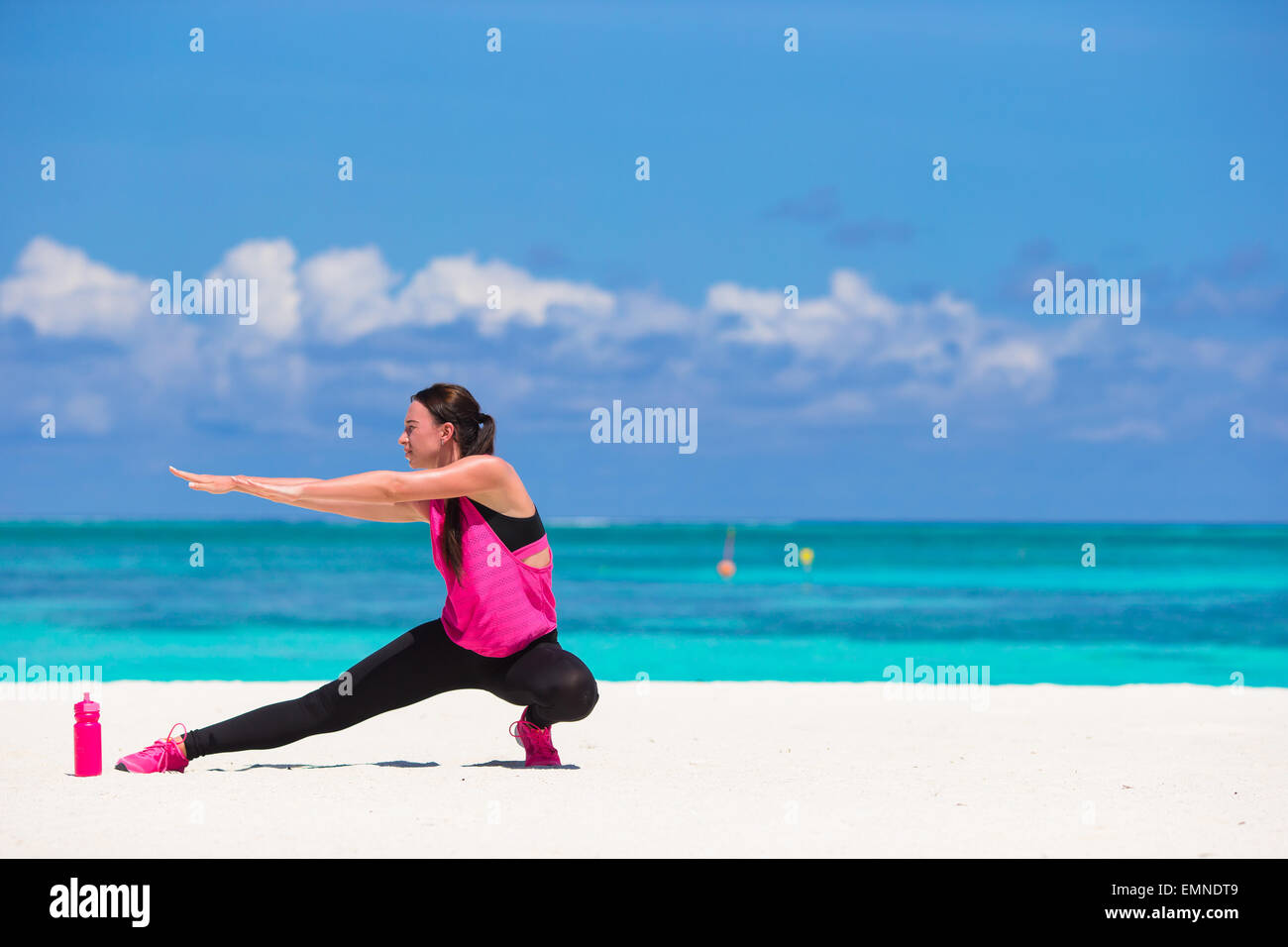 Fit young woman doing exercises on tropical white beach in her ...