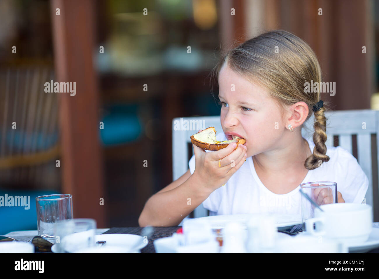 Little adorable girl eating bread with butter and honey on breakfast ...