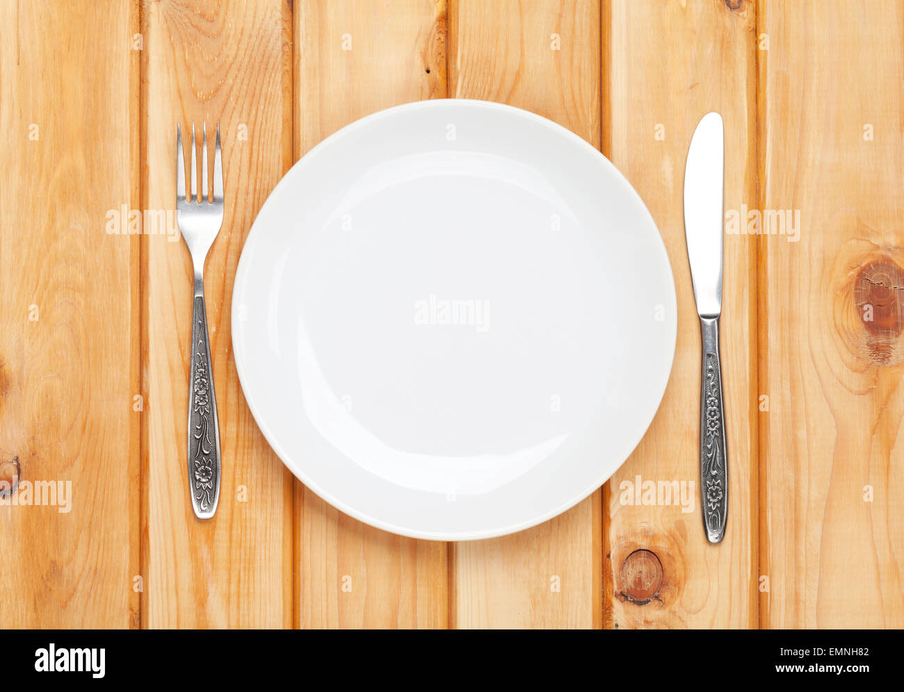 Empty plate and silverware over wooden table background. View from ...