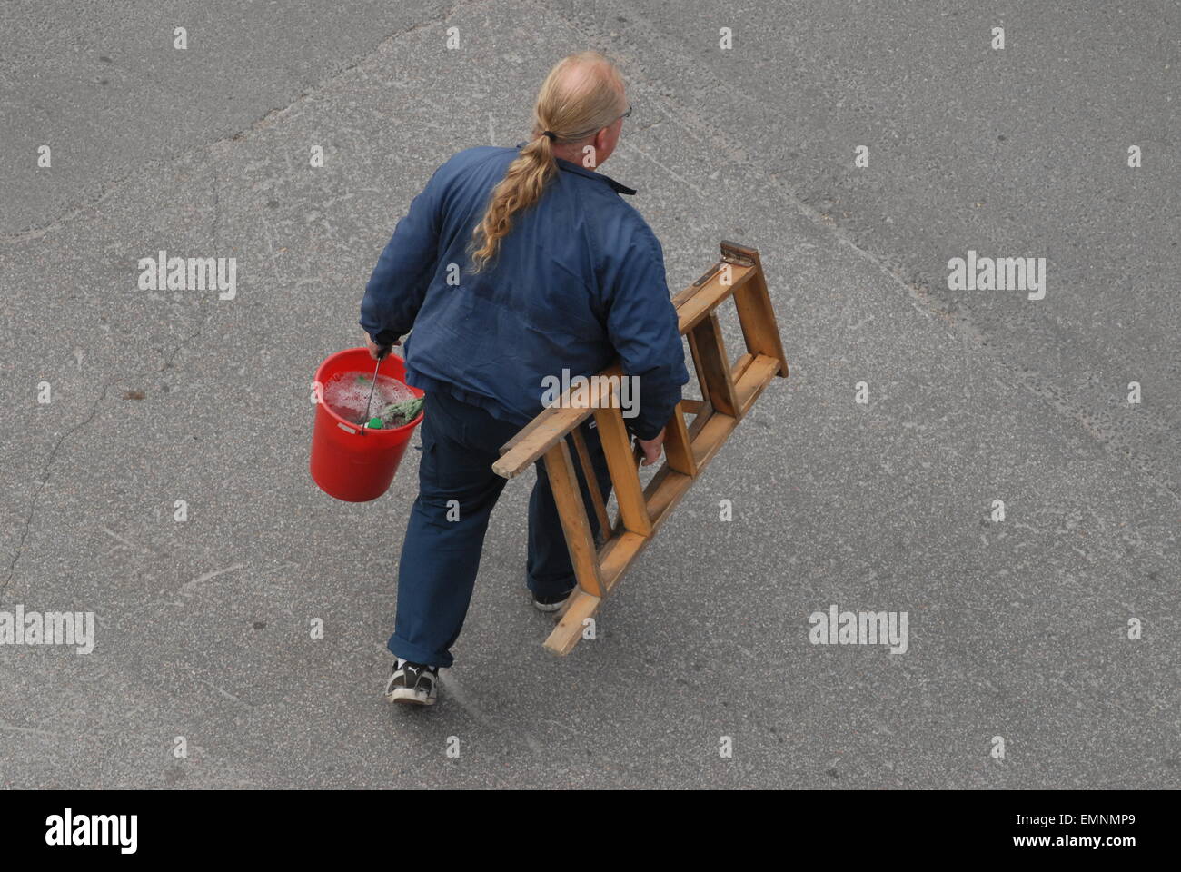 Window cleaner carrying a red water bucket and a wooden ladder Stock ...