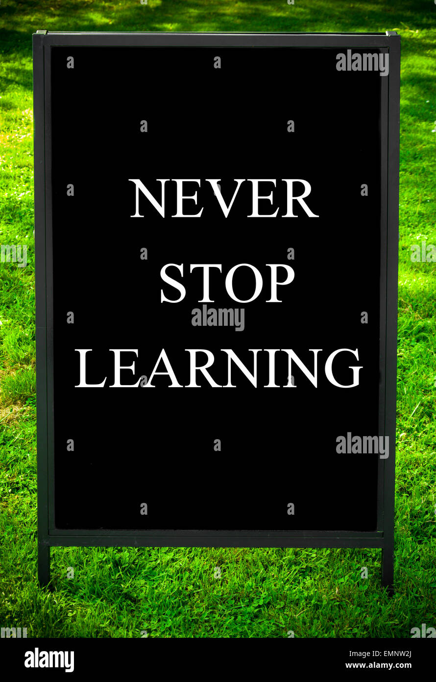 NEVER STOP LEARNING message on sidewalk blackboard sign against green ...