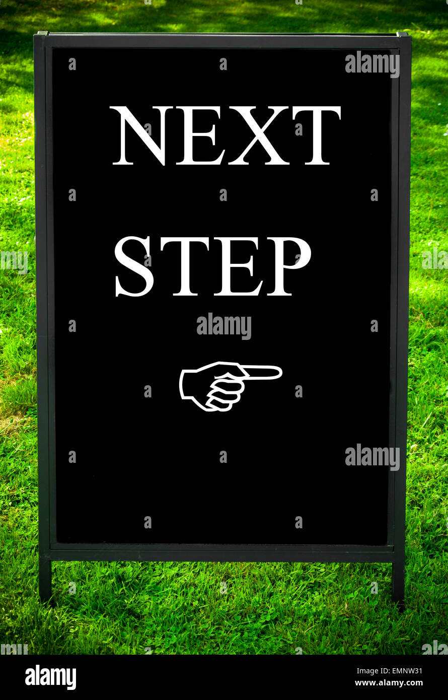 NEXT STEP message and hand pointing to the right on sidewalk blackboard ...