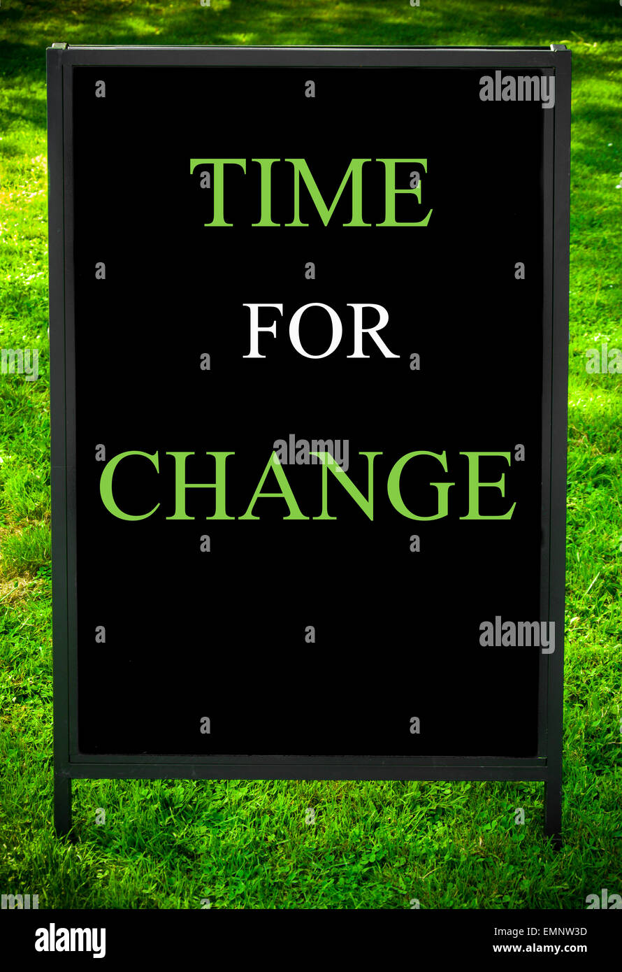 TIME FOR CHANGE message on sidewalk blackboard sign against green grass ...
