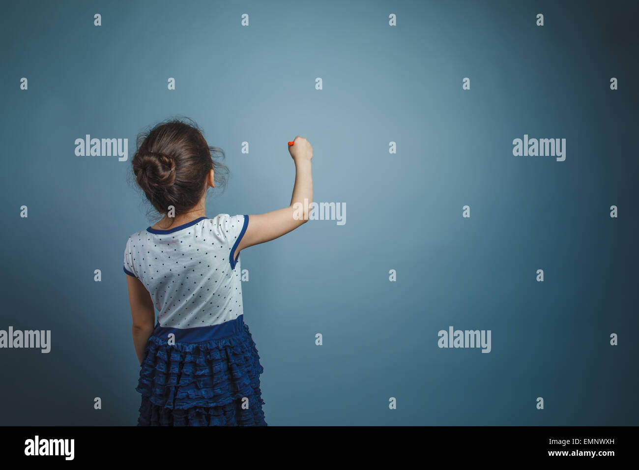 a girl of seven European appearance brunette writes back view on gray ...