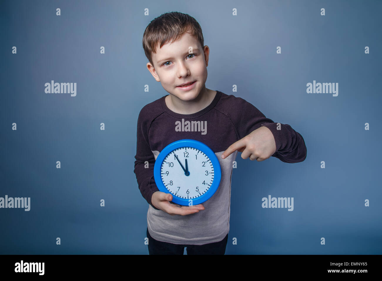 boy teenager European appearance holds a clock pointing at the blue ...